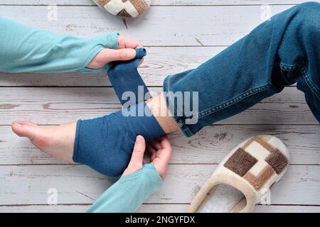 Feet trauma, injury. Adult wrapping compression bandage around sprained ...