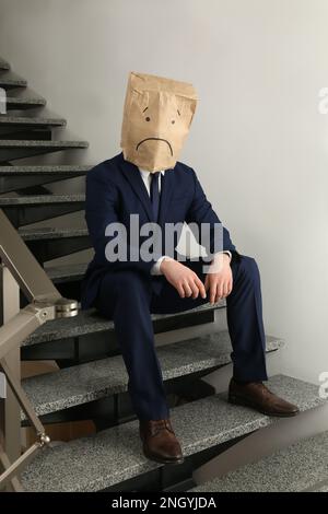 Man wearing paper bag with drawn sad face on grey background Stock ...
