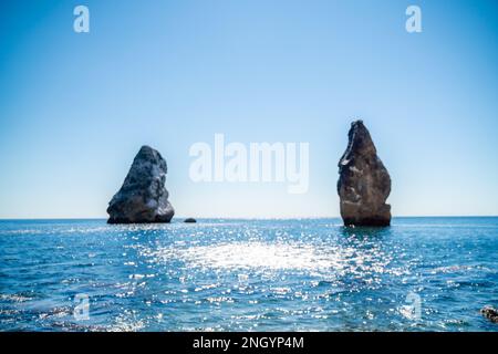 Two rocks stick out of the water in the middle of the turquoise sea ...