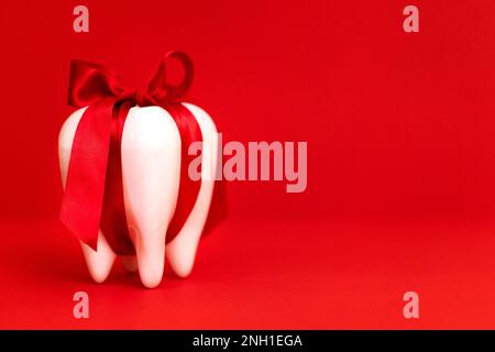 Tooth as a gift. Large white modal molar is tied with a red ribbon with ...