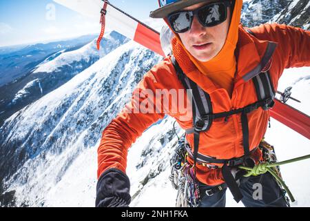 Ski-mountaineer organizing ropes with snowy mountains behind Stock ...