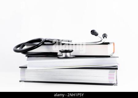 Stethoscope listening to stacked medicine books. White background with ...