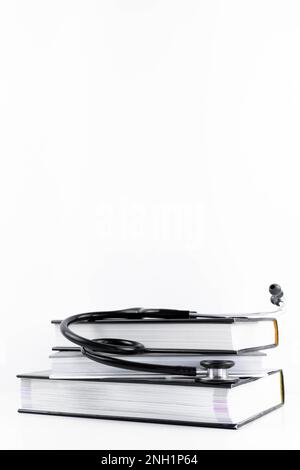Stethoscope listening to stacked medicine books. White background with ...