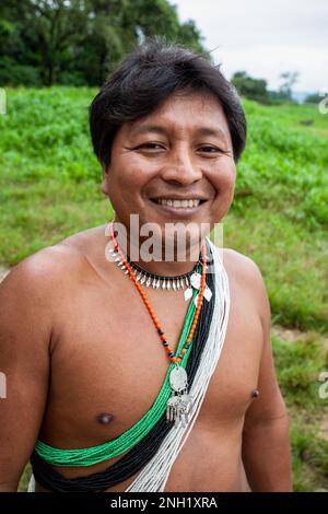 A young indigenous Embera man in traditional dress guides the dugout ...