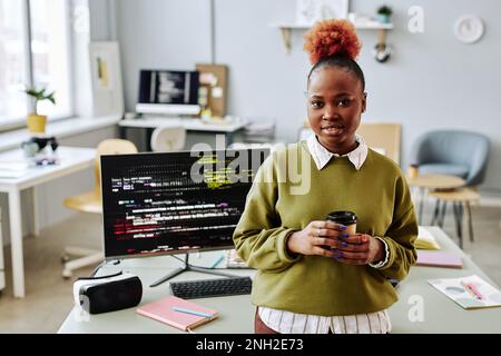 Smiling female software developer coding at desktop in bright modern ...