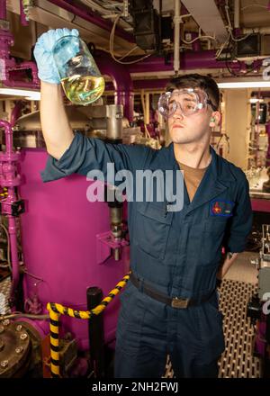 US Navy Airman inspects a sample of JP5 jet fuel from an F-A-18 Hornet ...