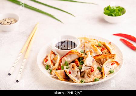 Fried dumplings served with green onions, sesame seeds and chili ...