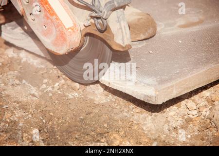 Builder cutting concrete slabs with petrol concrete saw and a diamond ...