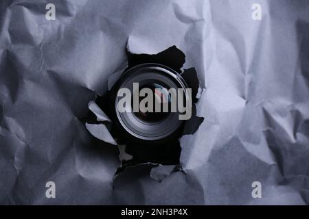 Hidden camera spying through torn hole in yellow paper, space for text ...
