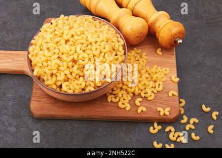 Elbow macaroni on a stone black background Stock Photo - Alamy