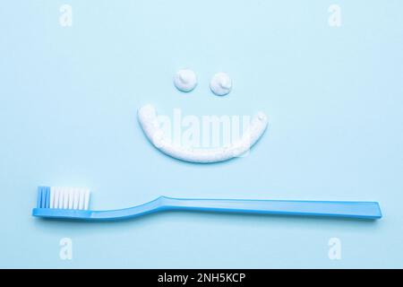 Funny face made with toothpaste and brush on pink background, flat lay ...