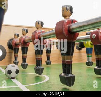 A vintage wooden foosball table with detailed metal player figurines in ...