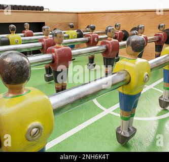 A vintage wooden foosball table with detailed metal player figurines in ...