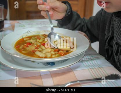 boy eating with a spoon a dish of beans Stock Photo - Alamy