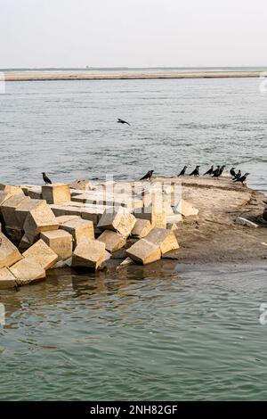 Granite bolder in infront of river. A pile of four square cinder blocks ...