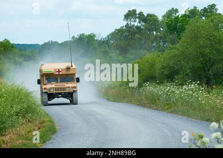 An M997A3 tactical Humvee ambulance races down a gravel road toward a ...