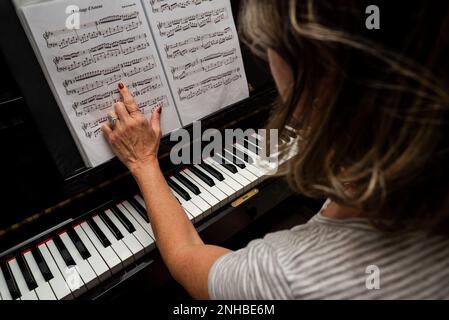 Talented woman pointing sheet music on the piano at home. Musicality ...