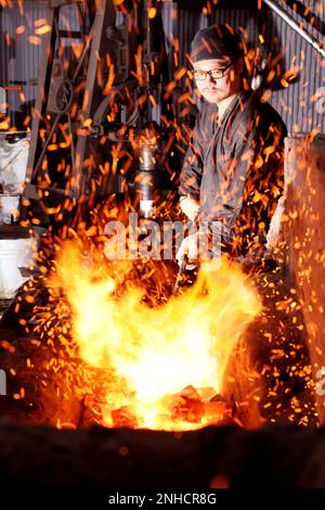 A sword smith Sukehira Hitara heats Tama-hagane iron at Hirata Sword ...