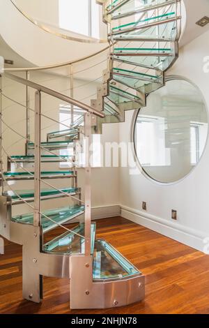 Steel and tempered glass twisting staircase against exotic wood ...