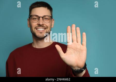 Left-handed man against light blue background, focus on palm with text ...
