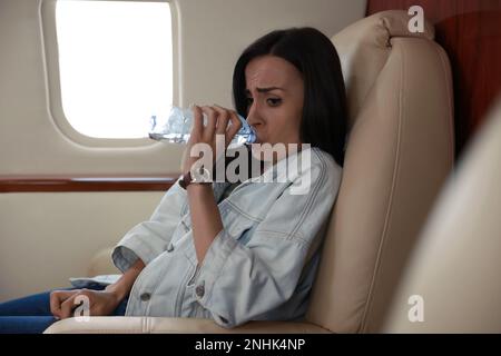 Nervous young woman with aviophobia drinking water in airplane Stock ...