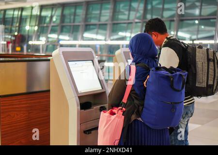 A couple checking-in flights using a smartphone at a self-check-in ...