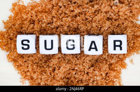 Sugar written in letter dice on brown sugar Stock Photo - Alamy