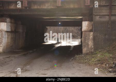 Street passing under a bridge with the silhouette of a town in the ...