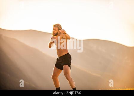 Man boxing with shadow exercising at sunset outdoor. Port victory ...