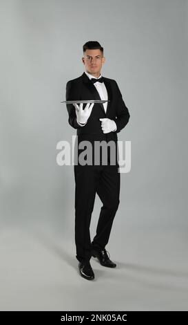 Handsome butler with tray on light grey background Stock Photo - Alamy