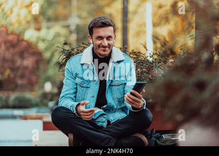 A gappy student sitting in a park using a smartphone and wireless ...
