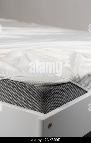 White satin sheet on an elastic band on the mattress. Bed linen on the ...