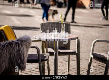 Empty tables outside between lunch hours along a cobblestone alley in a ...
