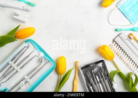 Frame made of dentist's tools and tulips on white background. Hello ...