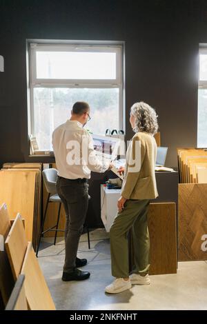 Two colleagues looking at printout of a house in architect's office ...