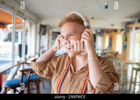 Non binary person listening to music using headphones showing and ...