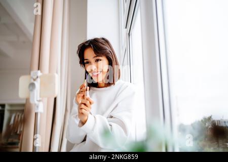 Happy influencer filming make-up tutorial through smart phone Stock ...