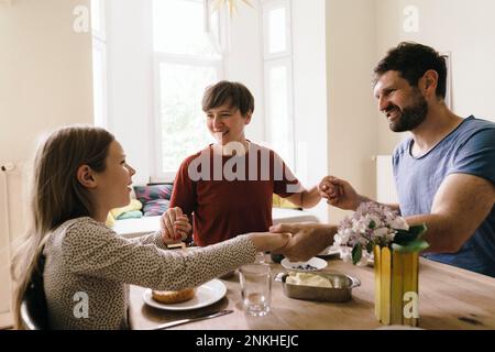 Happy family holding hands table Stock Photo - Alamy