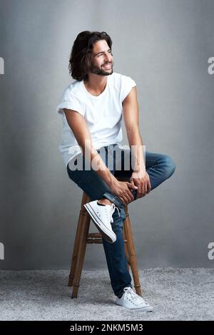 Handsome man sitting on stool against white background Stock Photo - Alamy