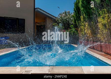 A huge splash of water is created by a cannonball dive into a swimming ...