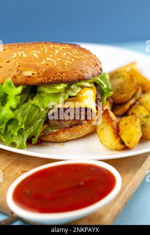 Homemade imperfect burger with potatoes and salad on a plate. Food on ...