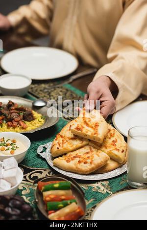 Cropped view of muslim man taking pita bread during ramadan dinner at ...
