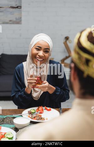 Interracial family smiling near delicious thanksgiving dinner and woman ...