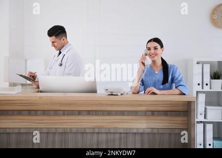 Receptionist and doctor working at countertop in hospital Stock Photo ...