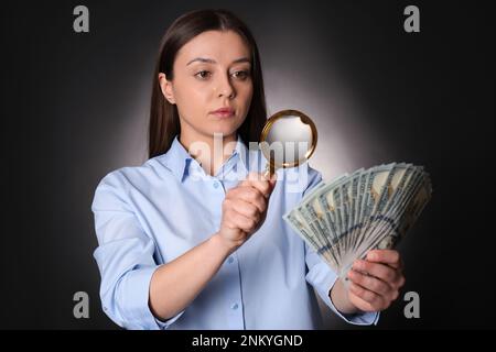 Expert authenticating 100 dollar banknotes with magnifying glass ...