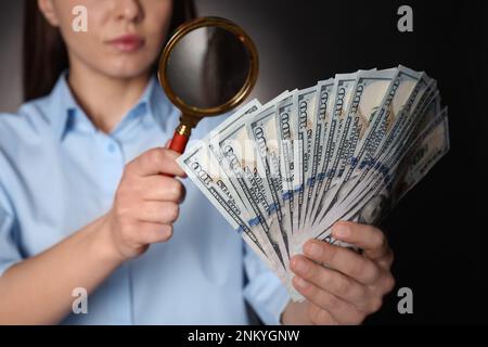 Expert authenticating 100 dollar banknotes with magnifying glass ...