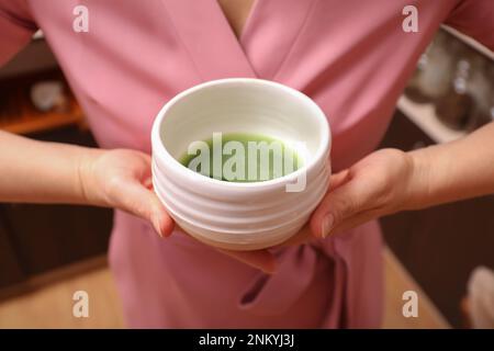 Master offering cup of freshly brewed beverage during traditional tea ...