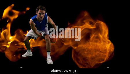 Composition of male basketball player crouching with ball over flames ...