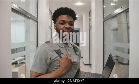 African CCTV cameras installer in uniform stands in corridor, smiles ...