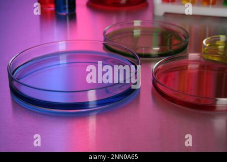 Petri dishes with colorful samples on desk, periodic table and chemical ...